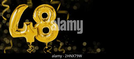 Gold foil balloon number number 48 on a background of black tinsel ...