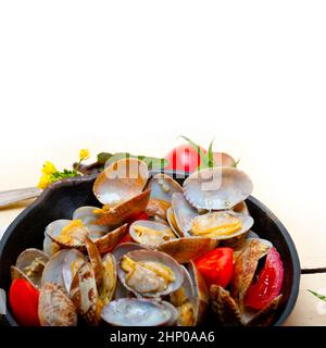 fresh clams stewed on an iron skillet over wite rustic wood table Stock ...