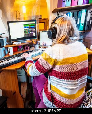 Female music producer composing music using computer software and ...