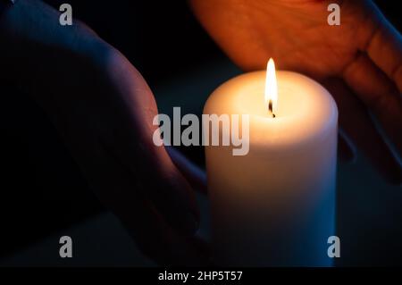 Hands warming at candle flame Stock Photo - Alamy