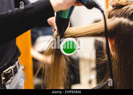 Master woman hairdresser dries the girl's hair with a hairdryer after ...