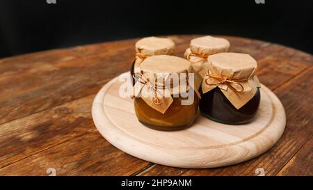 Four glass jars with different kinds of jam on wooden table. Homemade ...