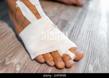 Man with foot wrapped in medical bandage on white background, closeup ...