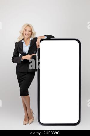 Businesswoman leaning on a big smartphone isolated on white background ...