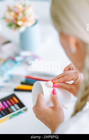 Cropped photo of hands of woman artist stained with red paint painting ...