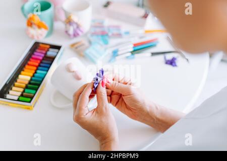 Cropped photo of hands of woman artist stained with red paint painting ...