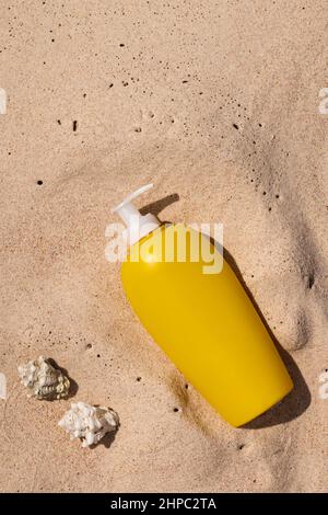 Yellow tube of suncream and seashells on the sand. UV and sunburn ...