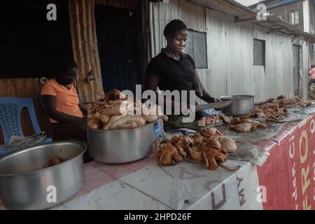 A woman sells fried chicken by the streets in Kibera Slums. Inside ...