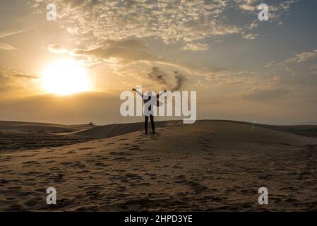 Woman throwing sand on the dunes of a beach at sunset. Freedom Stock ...