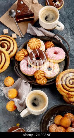 Table with various cookies, donuts, cakes, cheesecakes and coffee cups ...