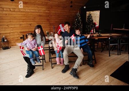 Family with Denmark flags inside wooden house sitting by table. Travel ...