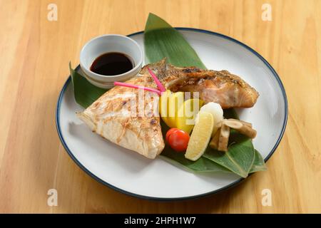 Hamachi cooked in sauce on black ceramic plate Stock Photo - Alamy