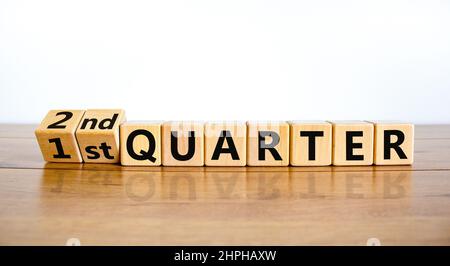 From 1st to 2nd quarter symbol. Businessman turns a wooden cube and ...