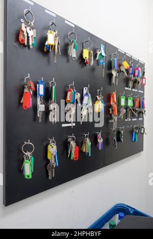 on a black key board hang many different keys with colorful key chains ...