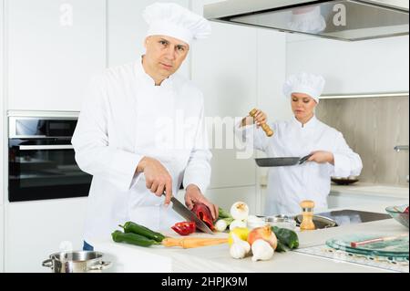 Two female and male cooks wearing uniform working on kitchen Stock ...
