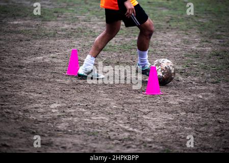 Footballer dribbling ball during training between cones. Young soccer ...