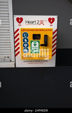 Yellow defibrillator box on an external brick wall of a shopping centre ...