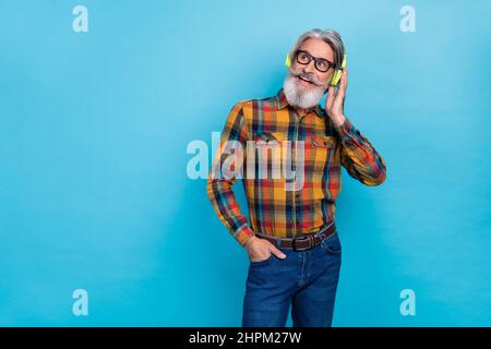 curious hipster man listen music in earphones isolated on yellow ...