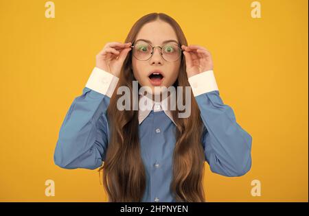 Shocked school aged girl child in spectacles with amazed look yellow ...