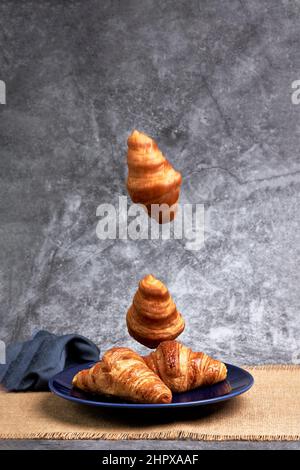 Group of croissants falling on a blue plate. Healthy breakfast. Sweets ...