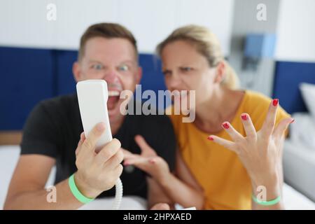 Couple yelling into phone while sitting on the bed in the hotel Stock ...
