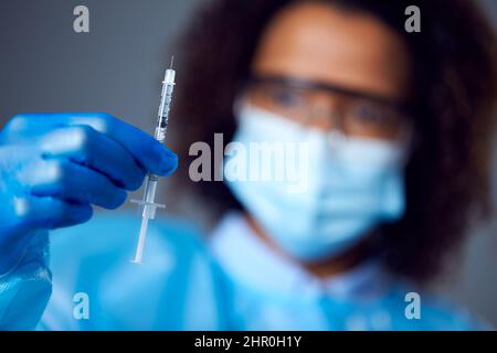 Female Lab Research Worker Wearing Lab Coat And PPE Holding Test Tube ...