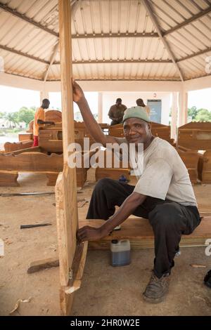 Adult male African woodworker plaining wood in a carpentry workshop in ...