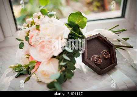 Beautiful bridal bouquet, a pair of golden wedding rings in a wooden ...