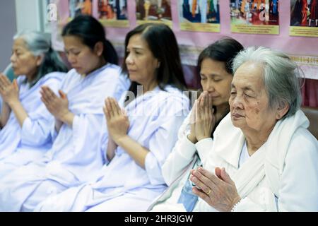 Buddhist women of various ages pray with their hands clasped. In a ...