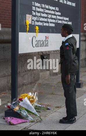 A cadet salutes after placing flowers outside the gates of the John ...