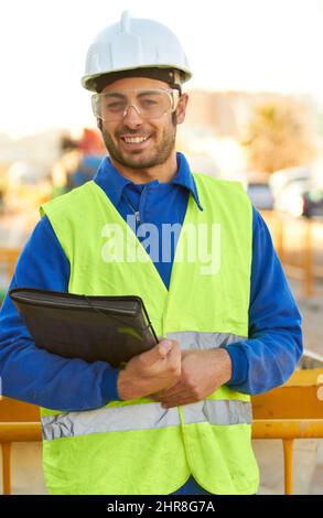 Overseeing a construction site. A handsome young contractor in a ...