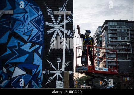 Anthony Ricciardi spray paints the eastern facade of a commercial ...