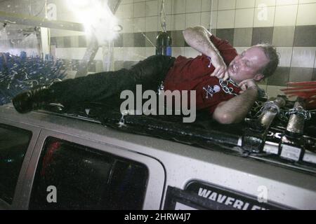 Escape artist Dean Gunnarson works at freeing himself from the roof of ...