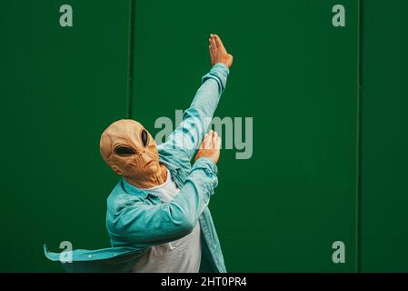 Alien doing dab posture and gesture against a green wall background ...