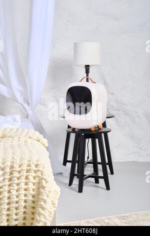 Compact and portable fridge on a chair near the bed in bedroom Stock ...