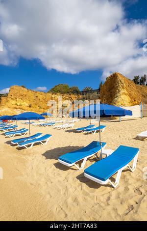 Scenic golden cliffs with umbrella and sunbathing in the Praia do Vau ...