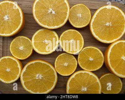 Vertical shot of freshly sliced seedless oranges on a wooden surface ...