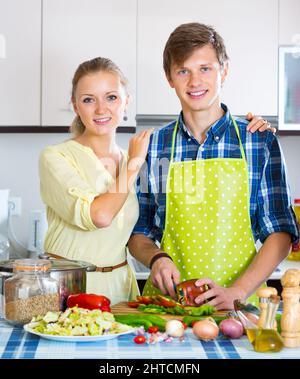 Young husband helping happy housewife to use washing machine at home ...