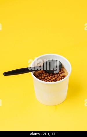White paper tub filled with sweet chocolate ice cream topped with small ...