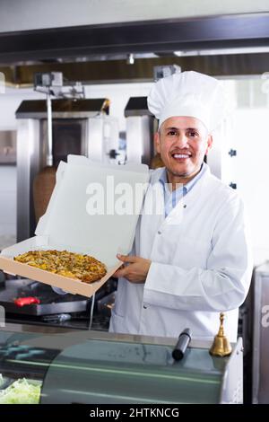 Positive man chef preparing pizza in pizzeria Stock Photo - Alamy