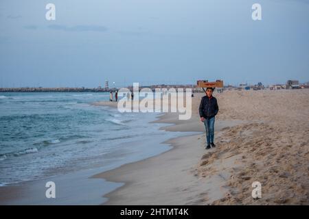 A Palestinian vendor walks on the Mediterranean beach during sunset in ...