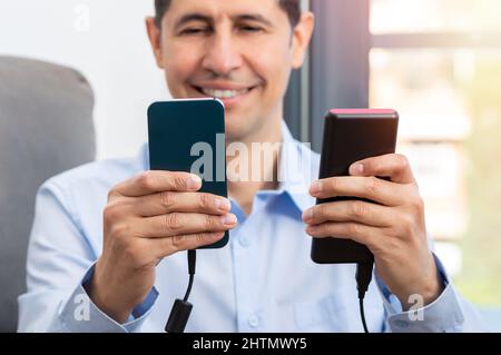 Man connecting USB charger to smart phone. Power bank, mobile phone ...