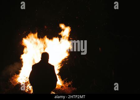 Silhouette shot of a male against fire in the field at night Stock ...