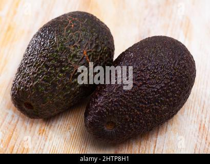 Two whole ripe avocados with dark bumpy skin. Close up still life of ...
