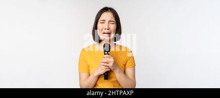 Crying asian girl singing heartbroken in microphone, holding mic and ...