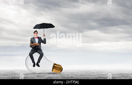 young businessman with an umbrella and a book Stock Photo - Alamy