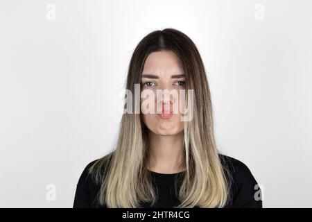 Confused woman, pursed lips, portrait on grey background, emotions ...