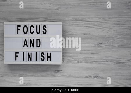 'Focus and Finish' on a lightbox on a white wooden background, top view ...