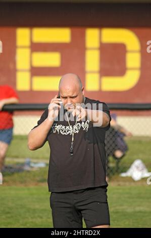 Shaved head football coach for little guys in full uniforms and pads ...