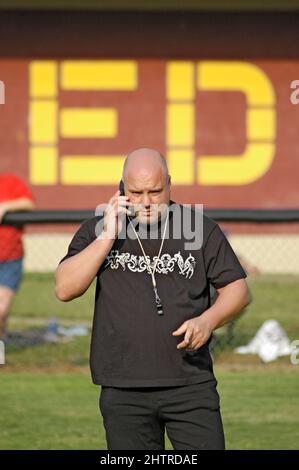 Shaved head football coach for little guys in full uniforms and pads ...